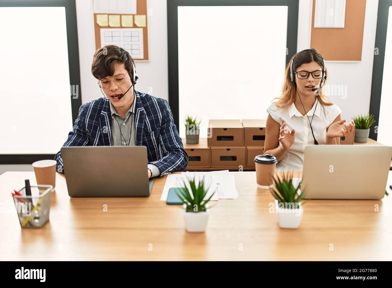 Two call center agents concentrated having video call using laptop at ...
