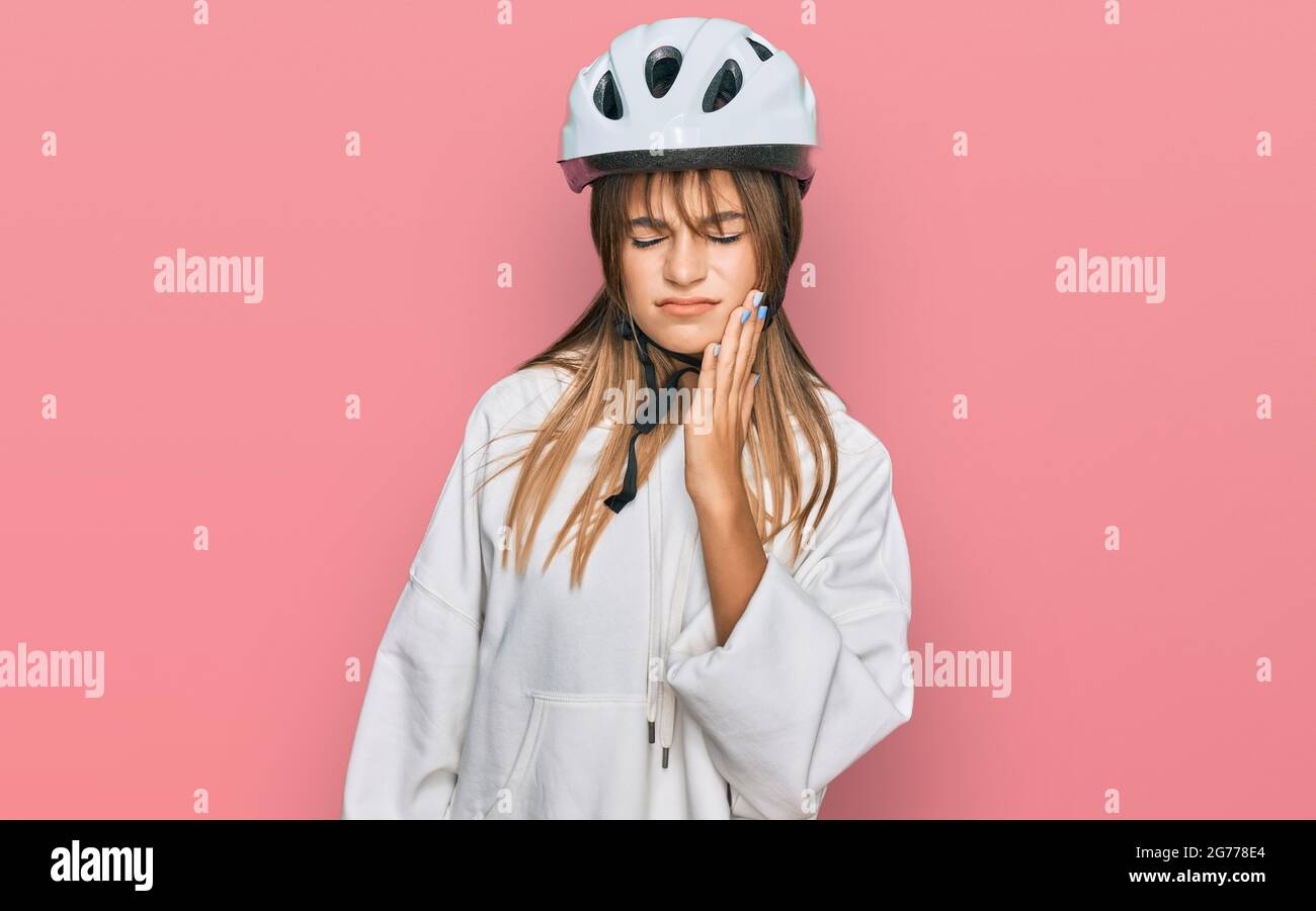 Teenager caucasian girl wearing bike helmet touching mouth with hand with painful expression ...