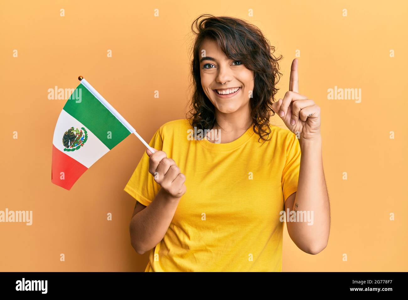 Young hispanic woman holding mexico flag smiling with an idea or ...