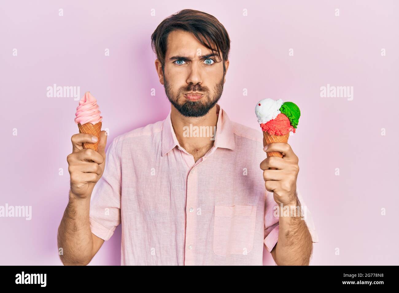 Young hispanic man holding ice cream puffing cheeks with funny face ...
