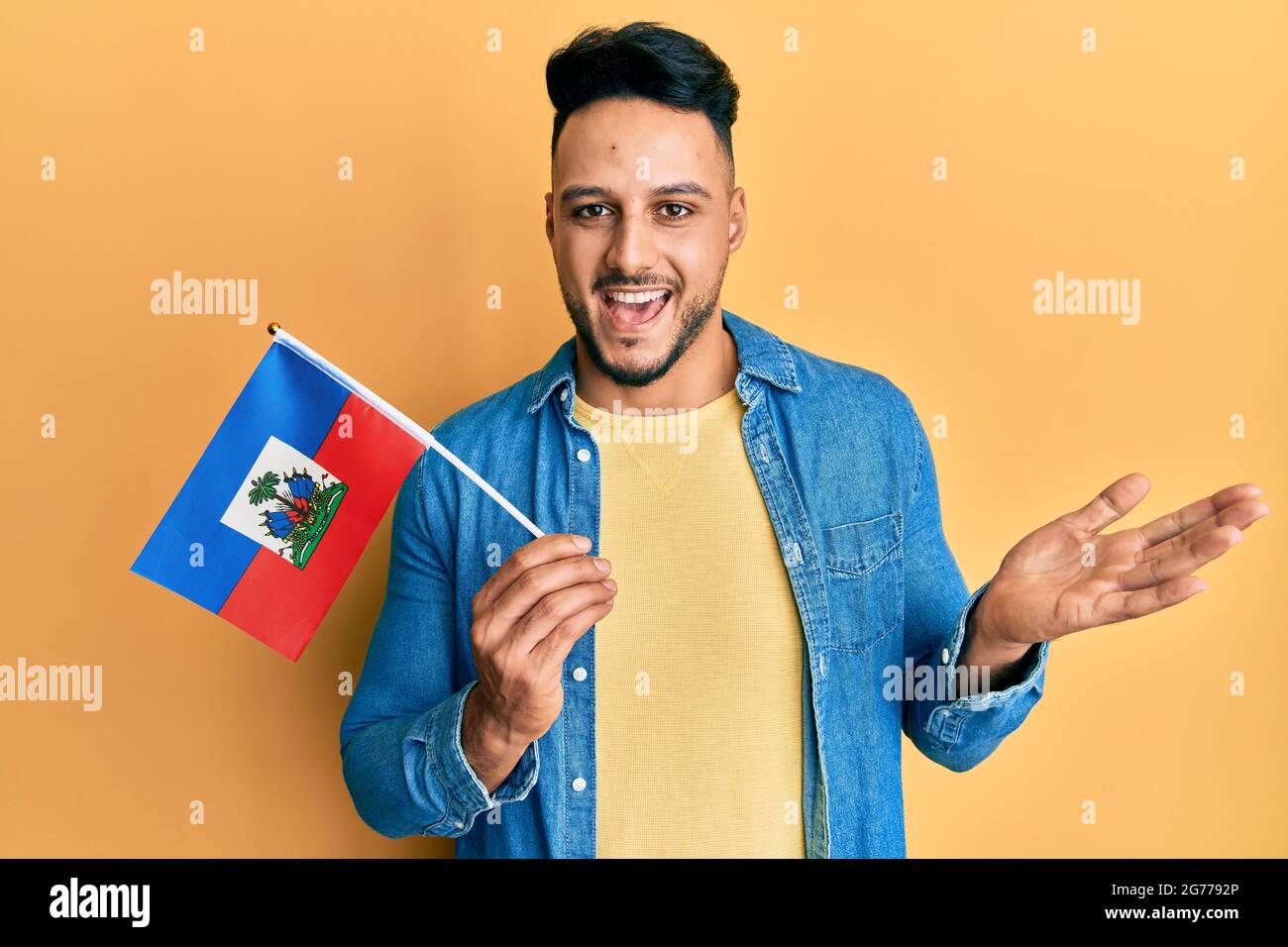 Young arab man holding haiti flag celebrating achievement with happy ...
