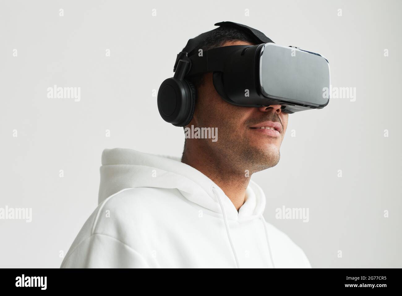 Minimal portrait of modern man wearing VR headset against white ...