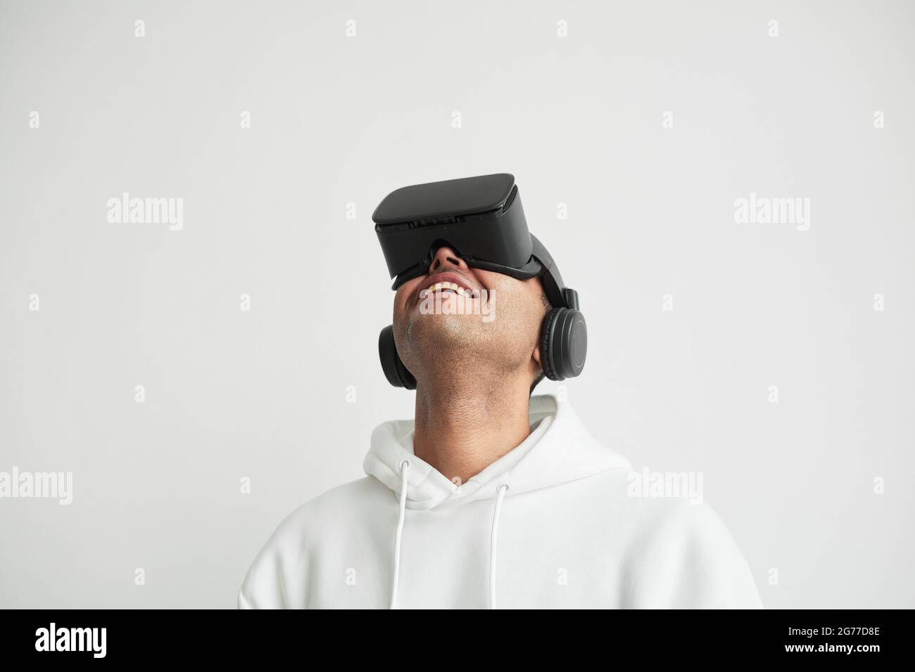 Minimal portrait of modern young man wearing VR headset against white ...