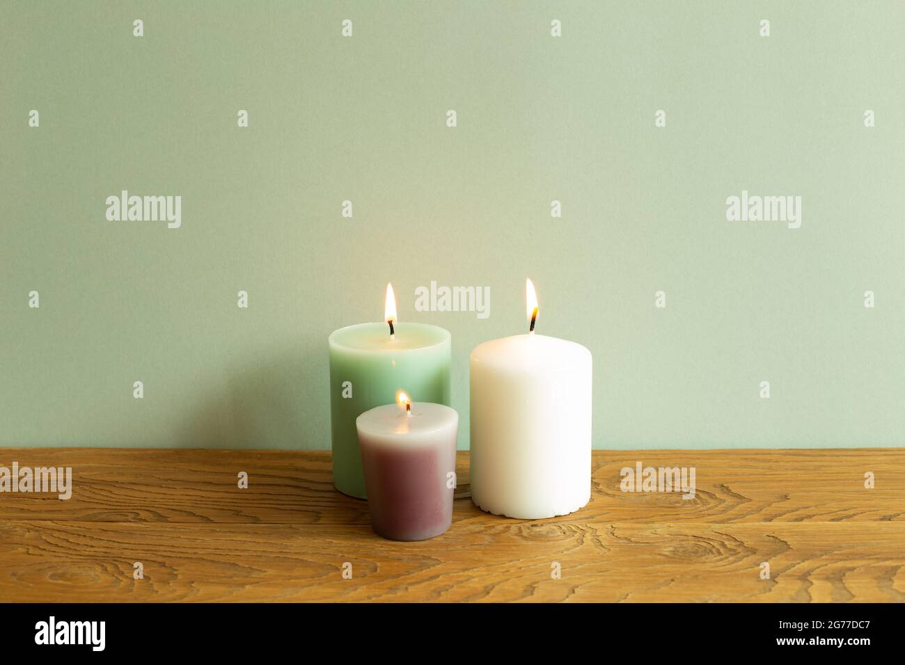 Color candles on wooden table. green wall background. home interior ...