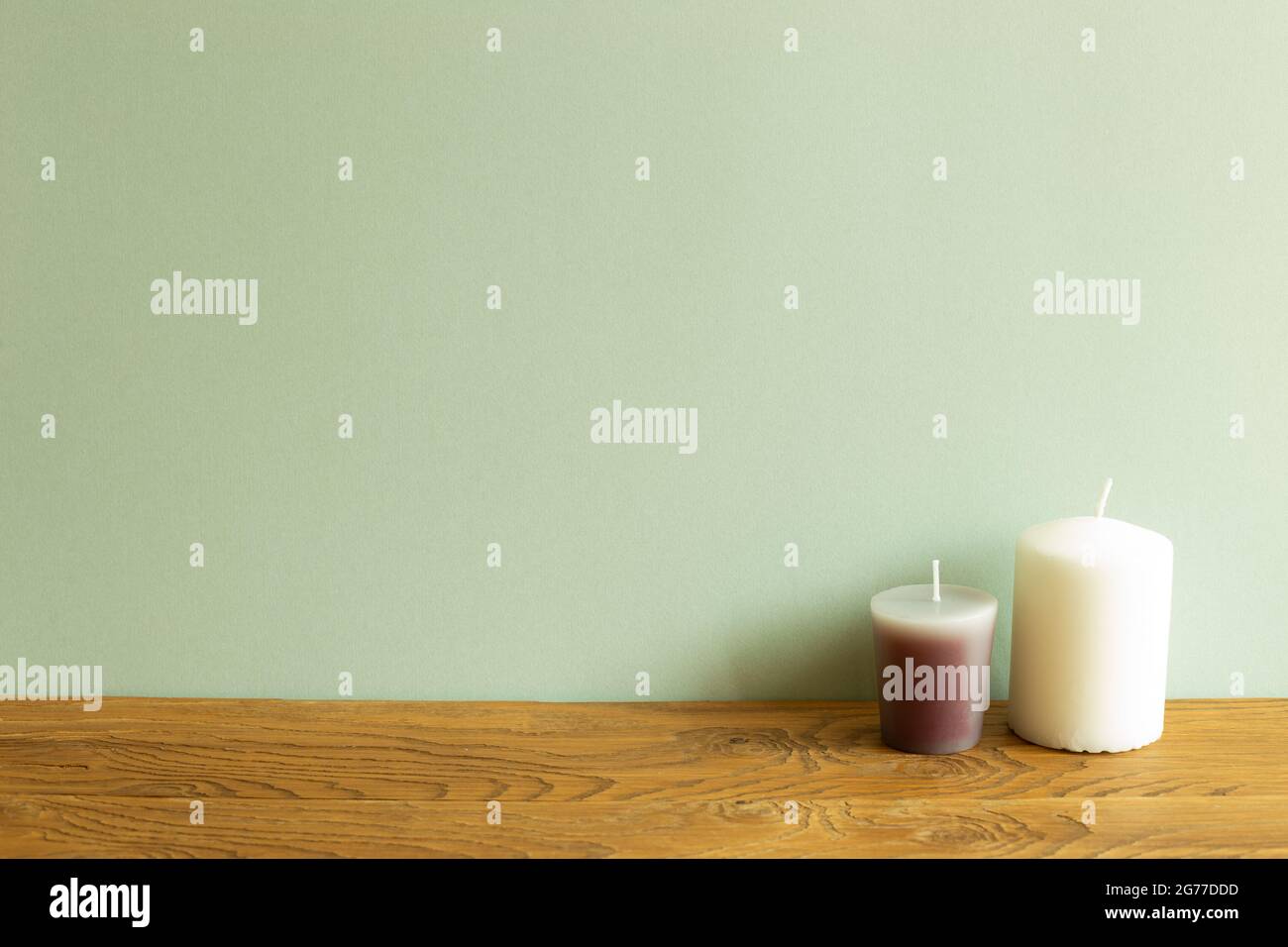 Color candles on wooden table. green wall background. home interior ...