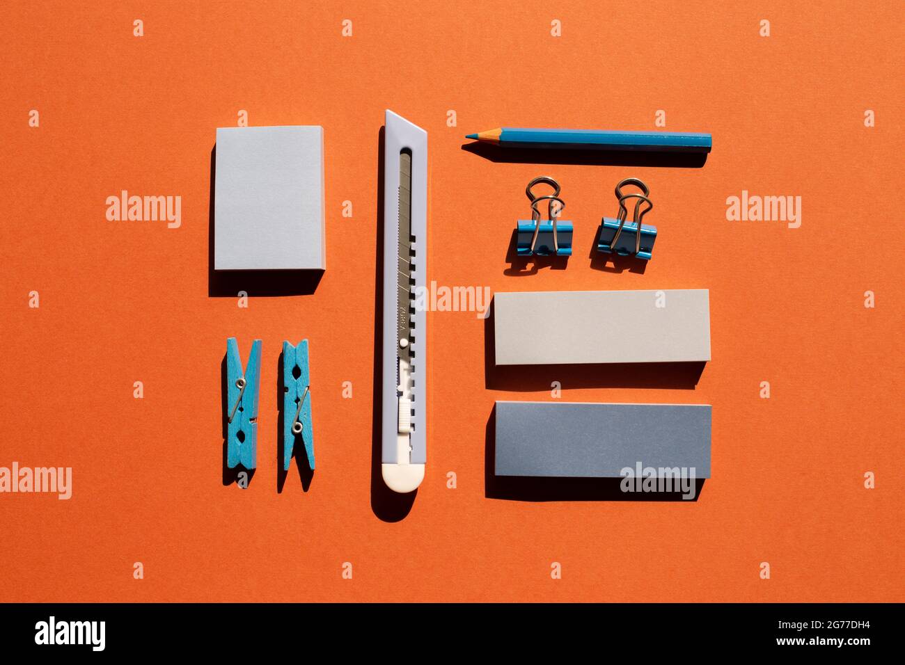 Blue memo notepad, clips, cutter, colored pencil on red background ...