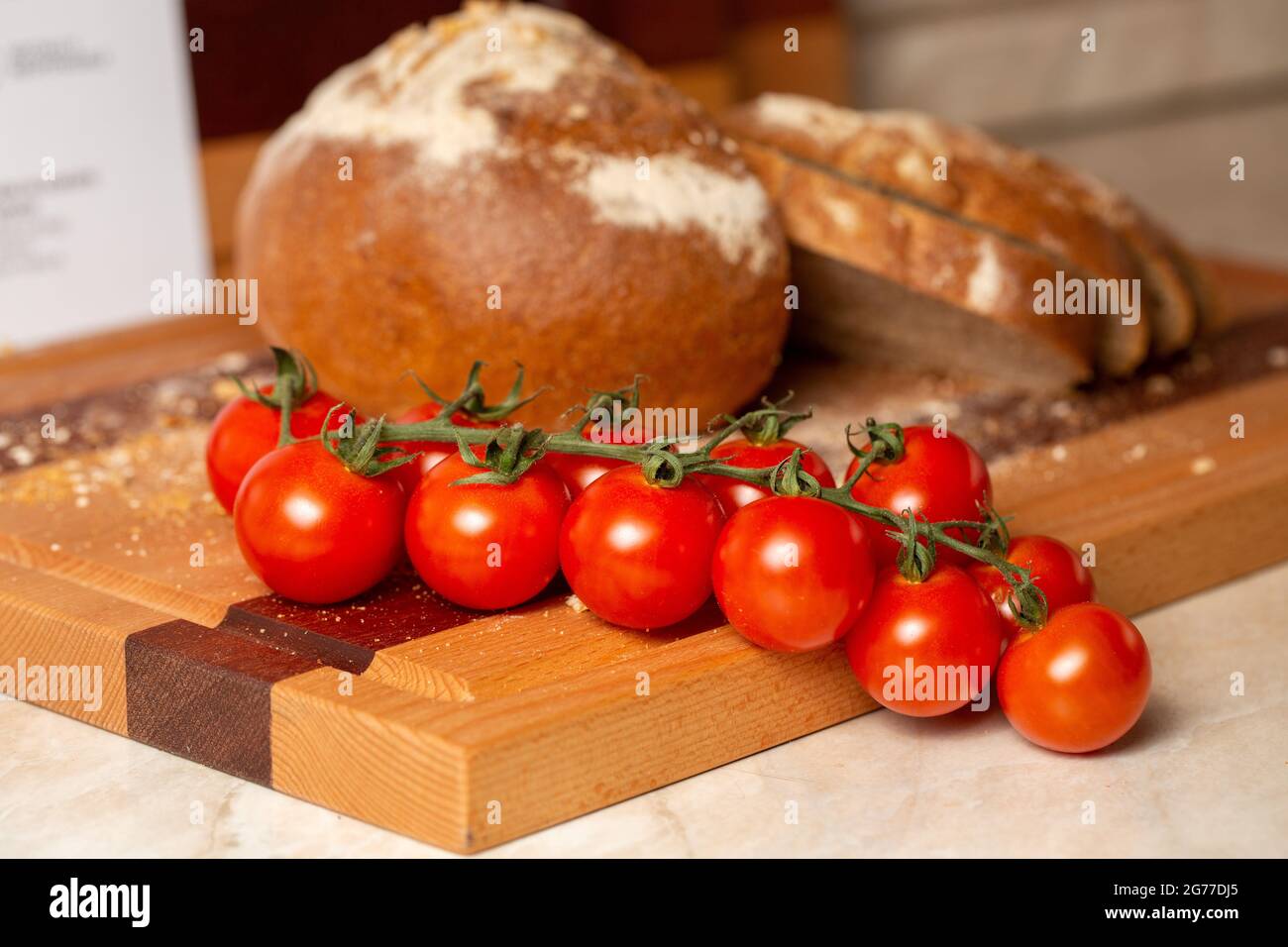 Closeup of fresh sliced bread and cherry tomatoes on a wooden cutting ...