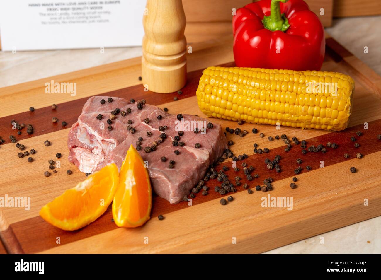 Closeup of fresh raw meat with orange slices and corn on a wooden ...