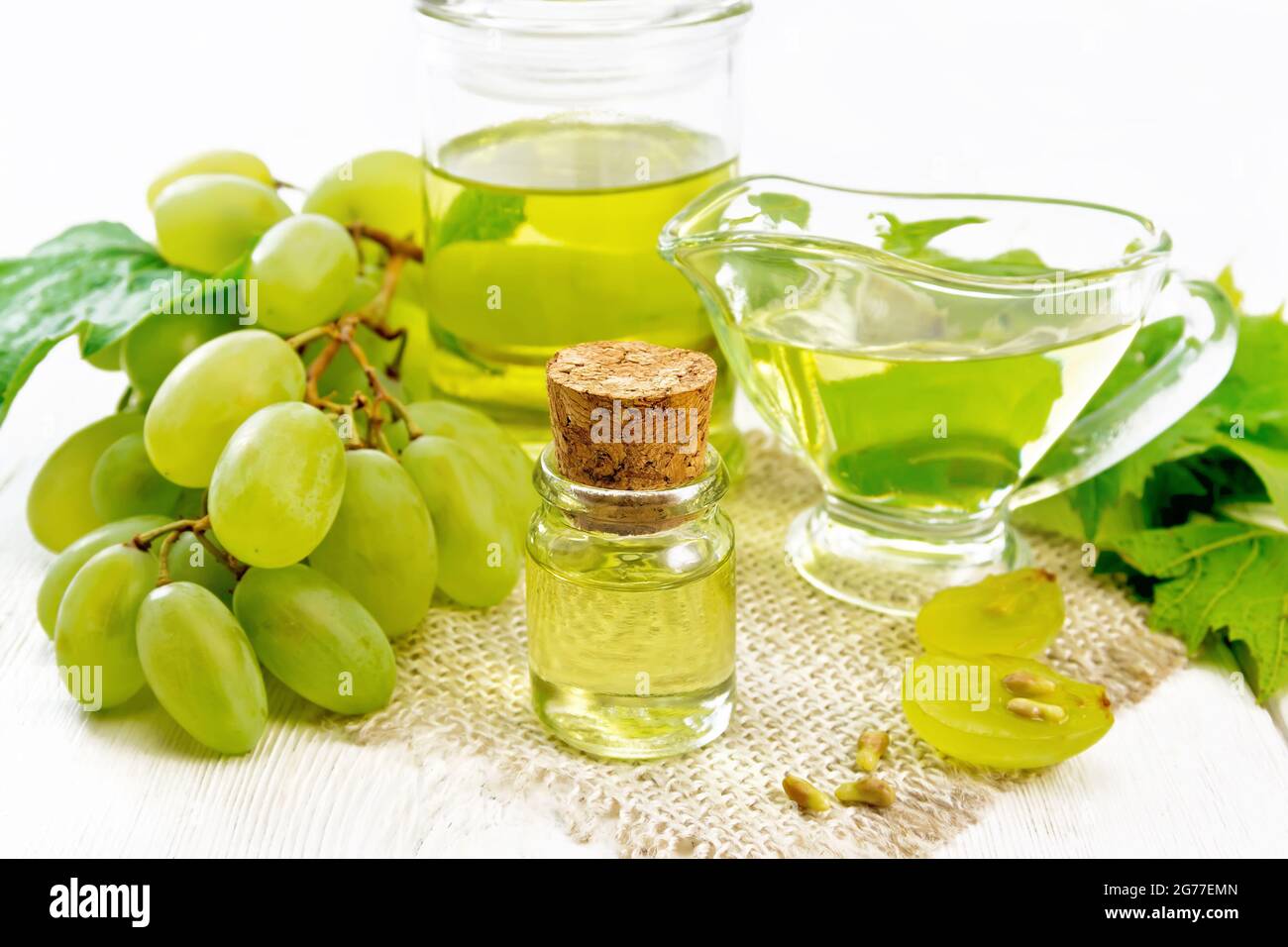 Grape oil in a bottle, gravy boat and a jar on a burlap napkin, berries ...