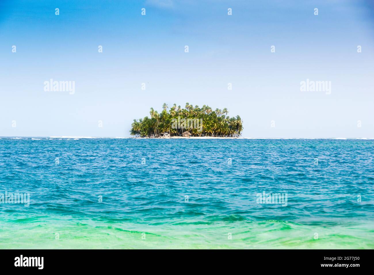 A small Caribbean island covered in palm trees in the horizon. Clear ...
