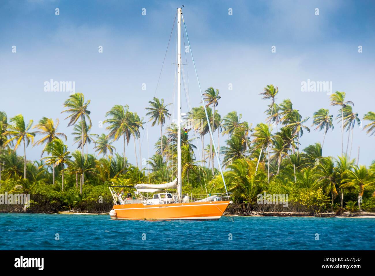 A small boat floating near the coast of a Caribbean island. Clear water ...