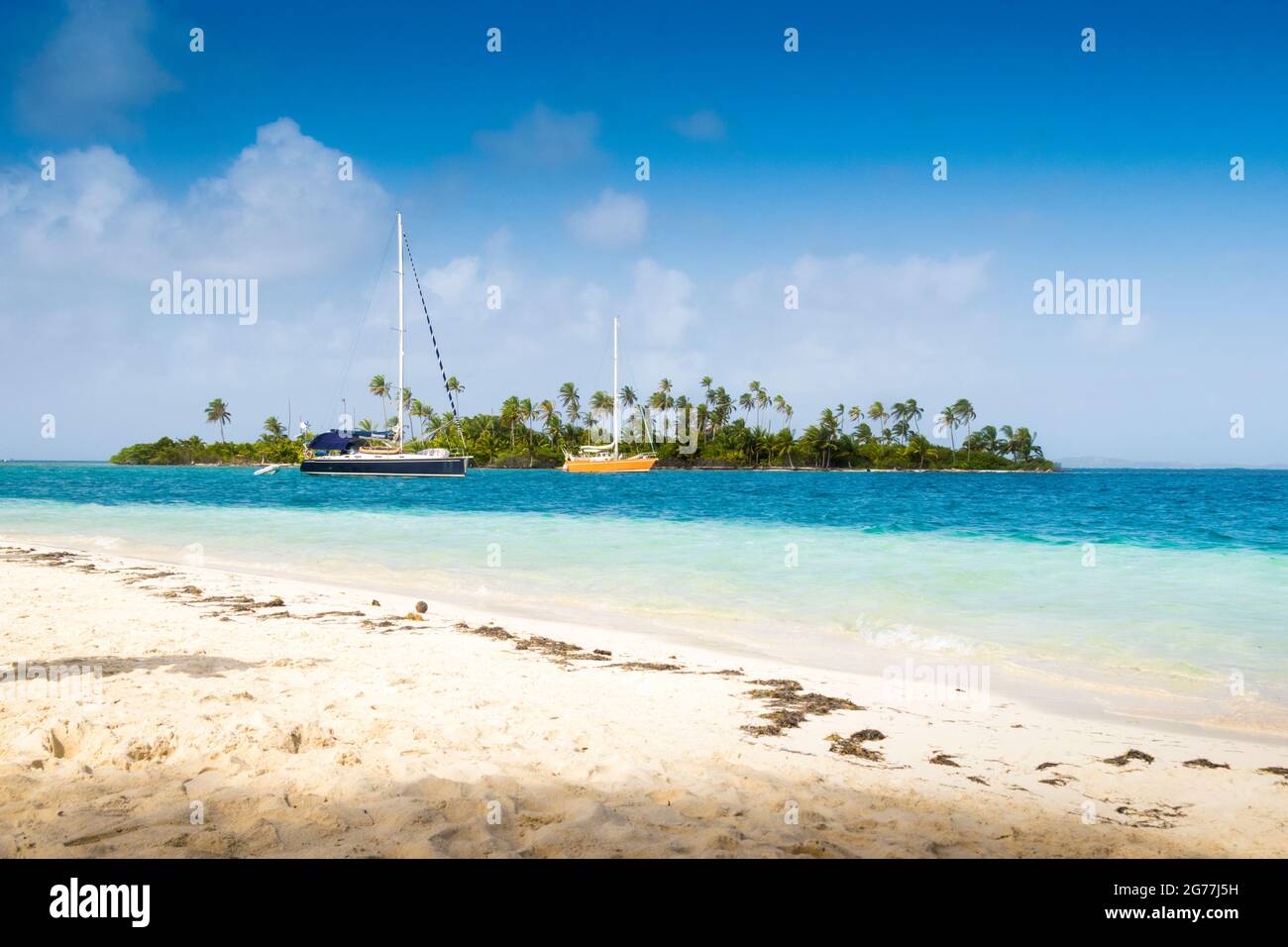 A small boat floating near the coast of a Caribbean island. Clear water ...