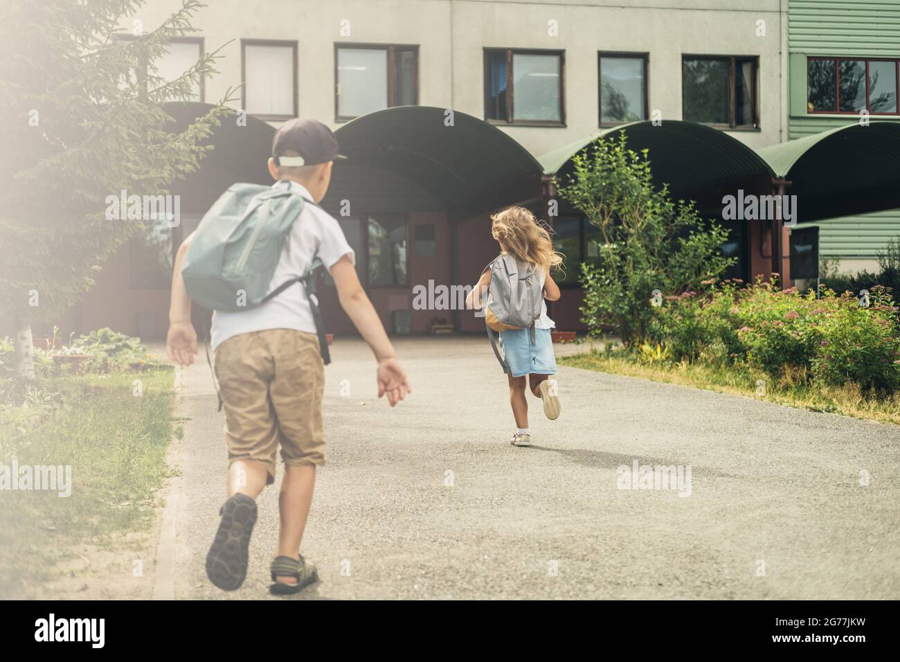 Two caucasian children, boy and girl, running to school with bags ...