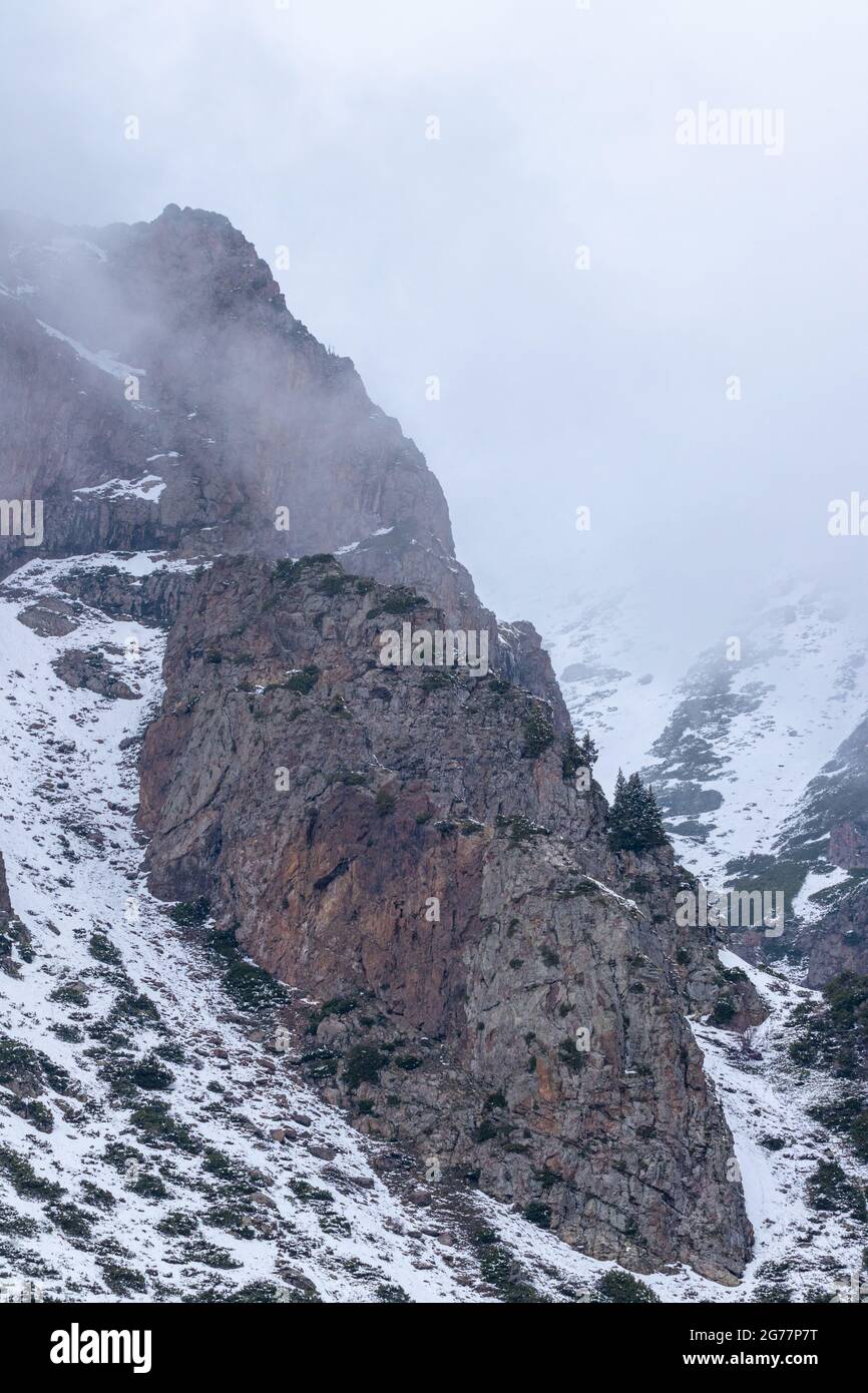Part of the slope of a mountain cliff with snow at the foot. Against ...