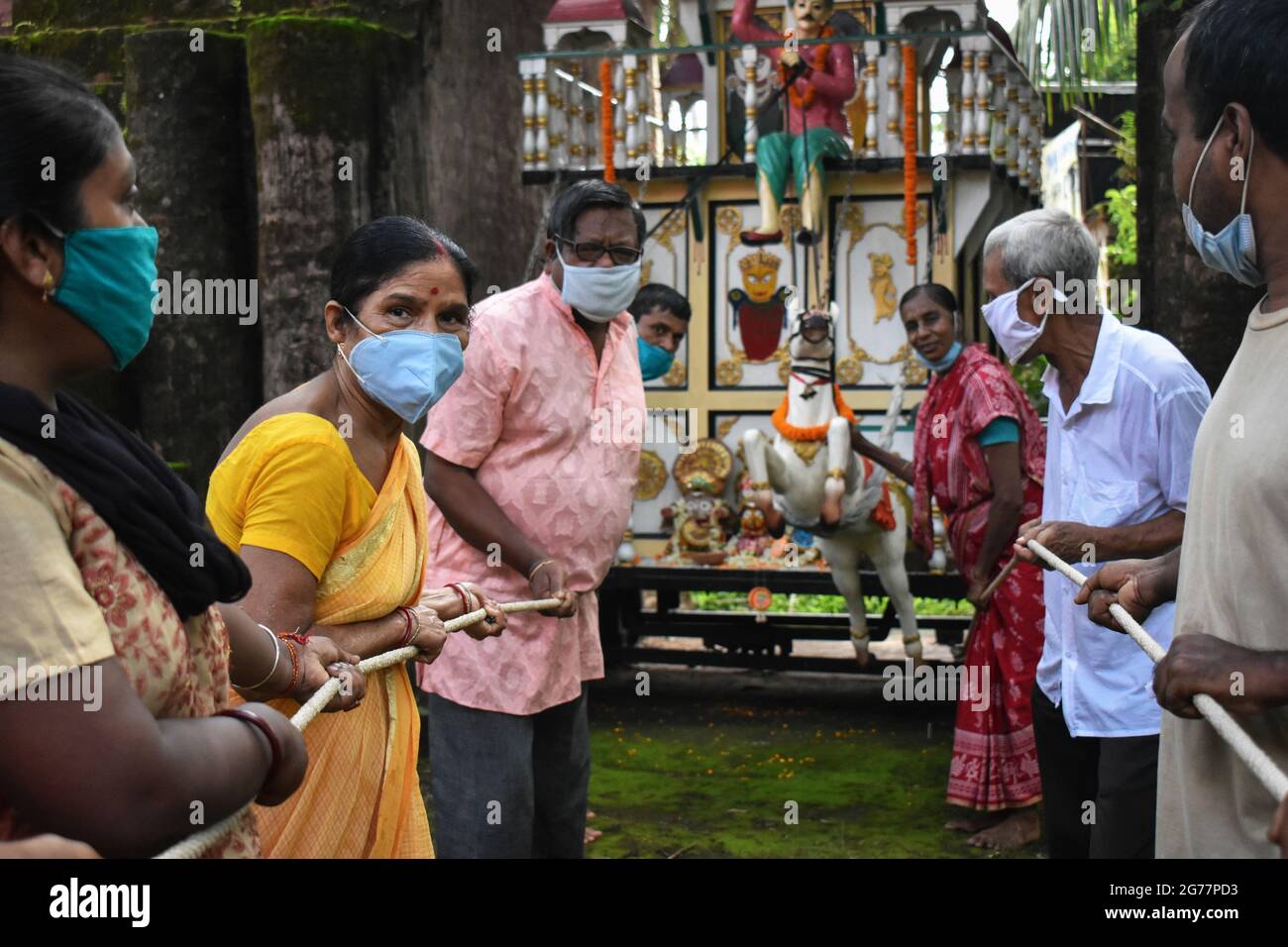 Kolkata, India. 12th July, 2021. Devotees are holding a rope to pull a ...