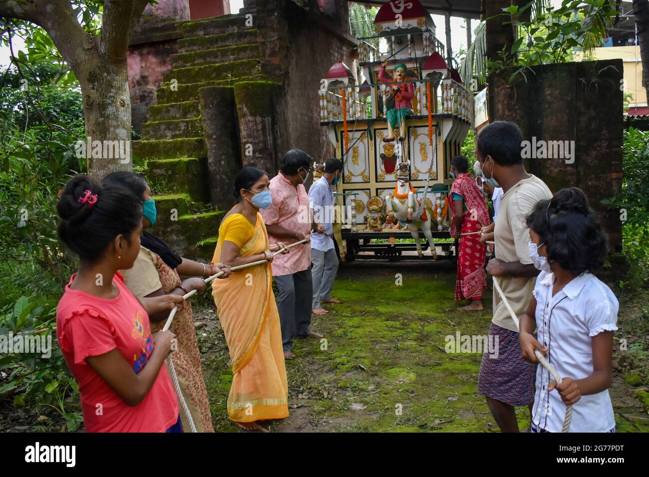 Kolkata, India. 12th July, 2021. Devotees are holding a rope to pull a ...