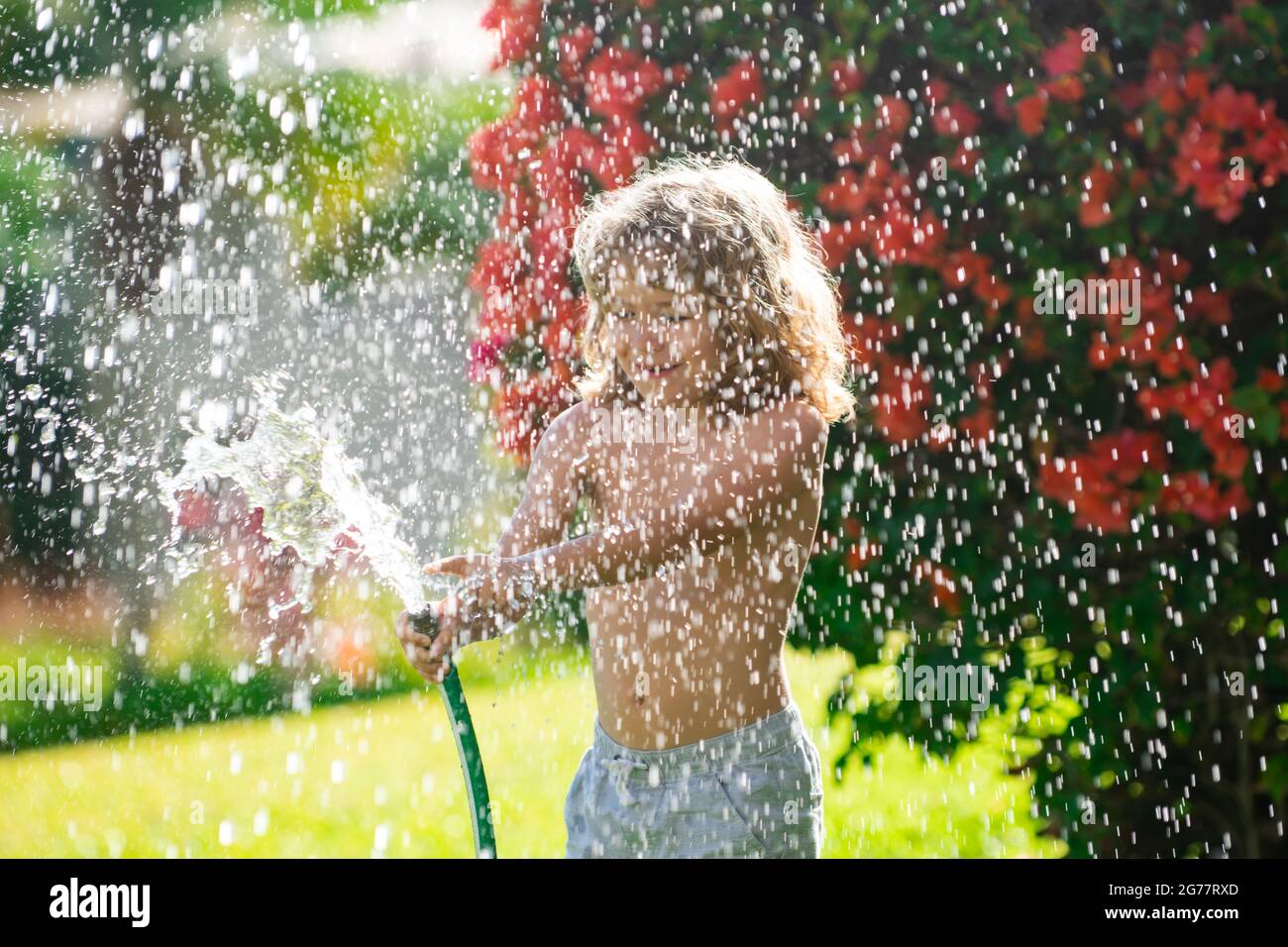 Kids play with water garden hose in yard. Outdoor children summer fun ...