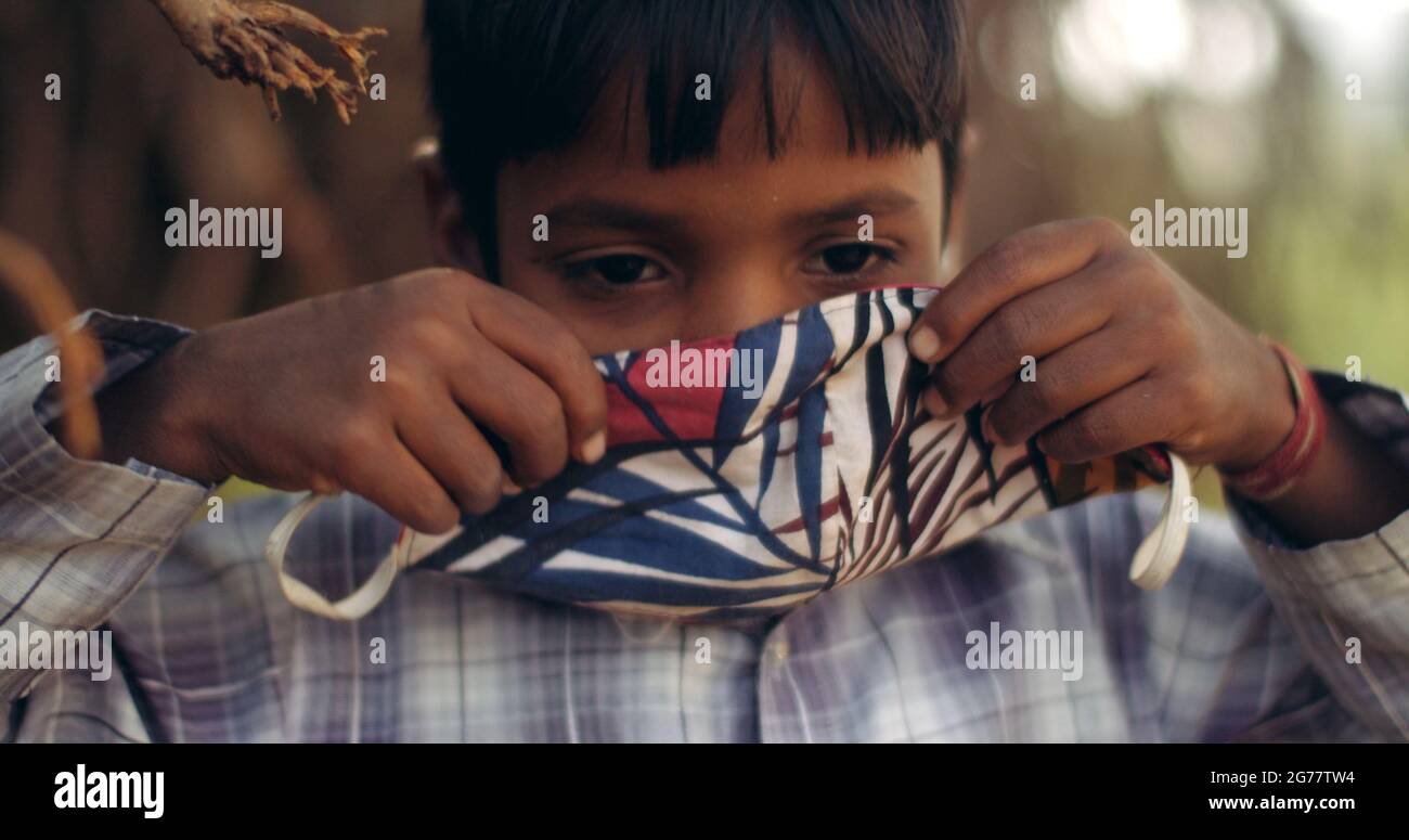 Closeup shot of an Indian boy putting on a mask- new normal concept ...