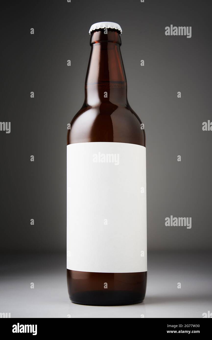 Beer bottle mockup. Full bottle of lager beer with blank labels on dark ...