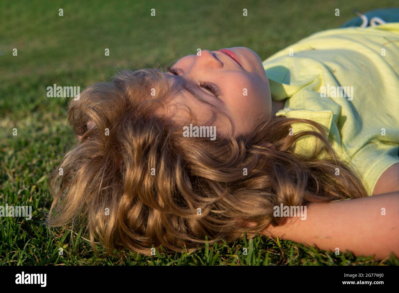 Portraits of happy kids playing and laying on grass outdoors in summer ...