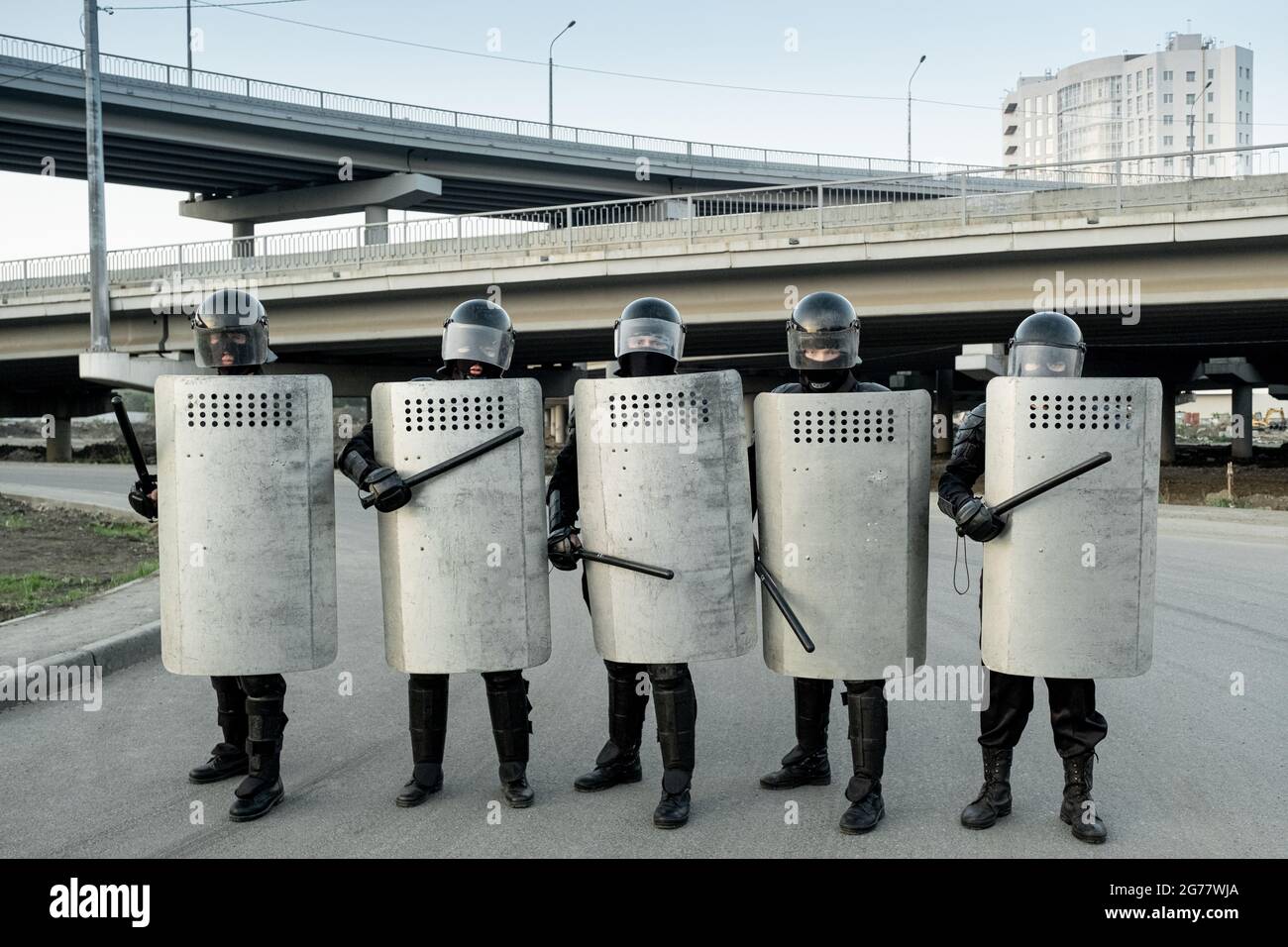 Group of police guards in uniform protected by shields standing with ...