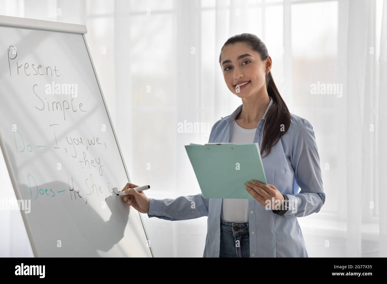 Teacher, tutor, coach looks at webcam, talking in classroom giving ...