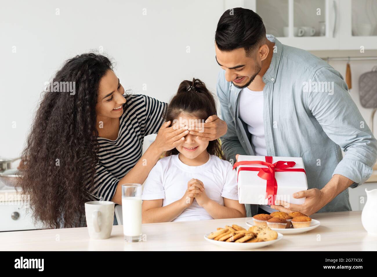 Young middle-eastern parents greeting their daughter with birthday ...