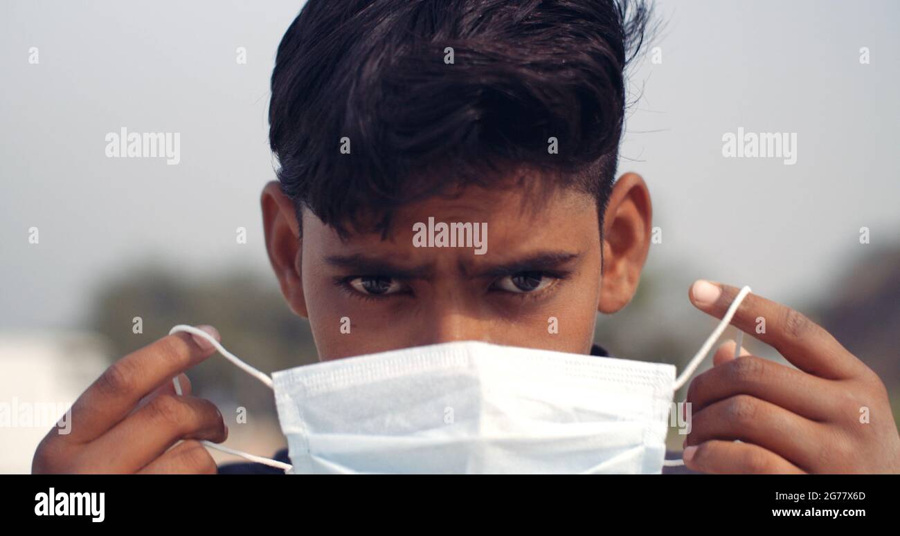 Closeup shot of an Indian boy putting on a mask- new normal concept ...