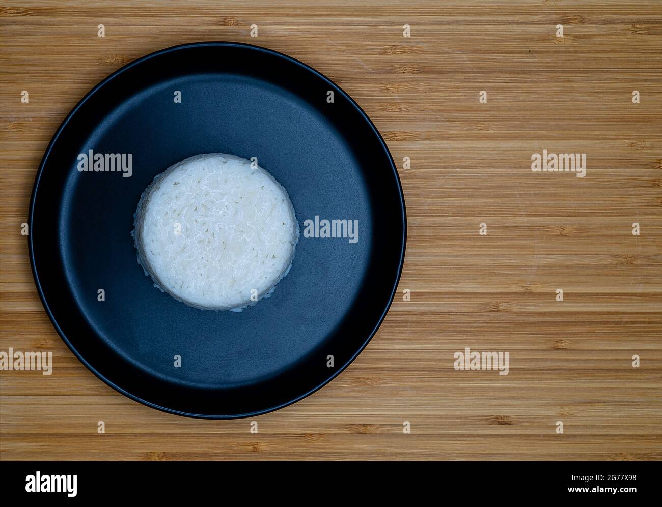 Thai style cooking steam rice put on black plate on wooden background ...