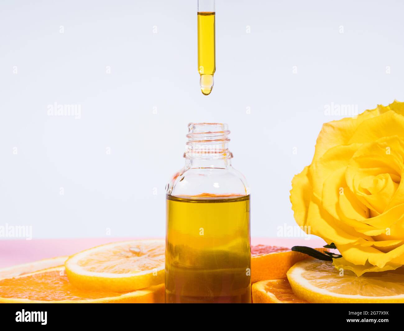 Vitamin C serum bottle with dropper on pink background with orange ...