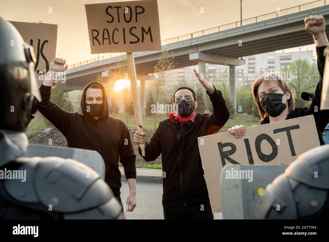 Group of displeased crowd in masks raising fists and screaming while ...