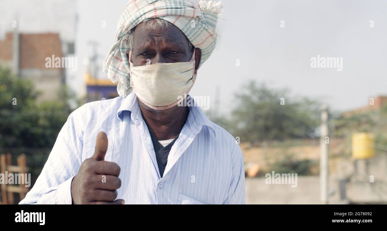Old Indian man wearing a face mask and showing thumbs up- new normal ...