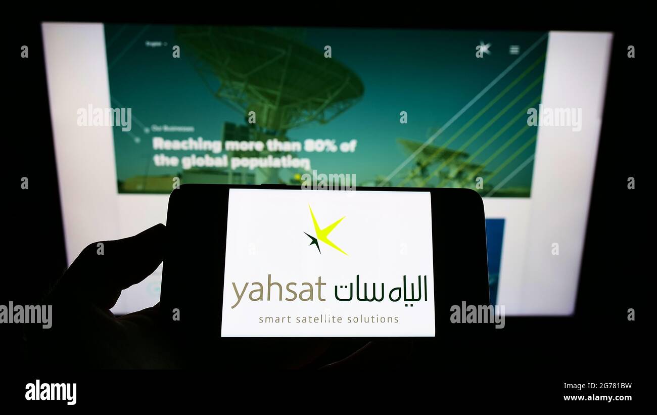 Person holding mobile phone with logo of Al Yah Satellite ...