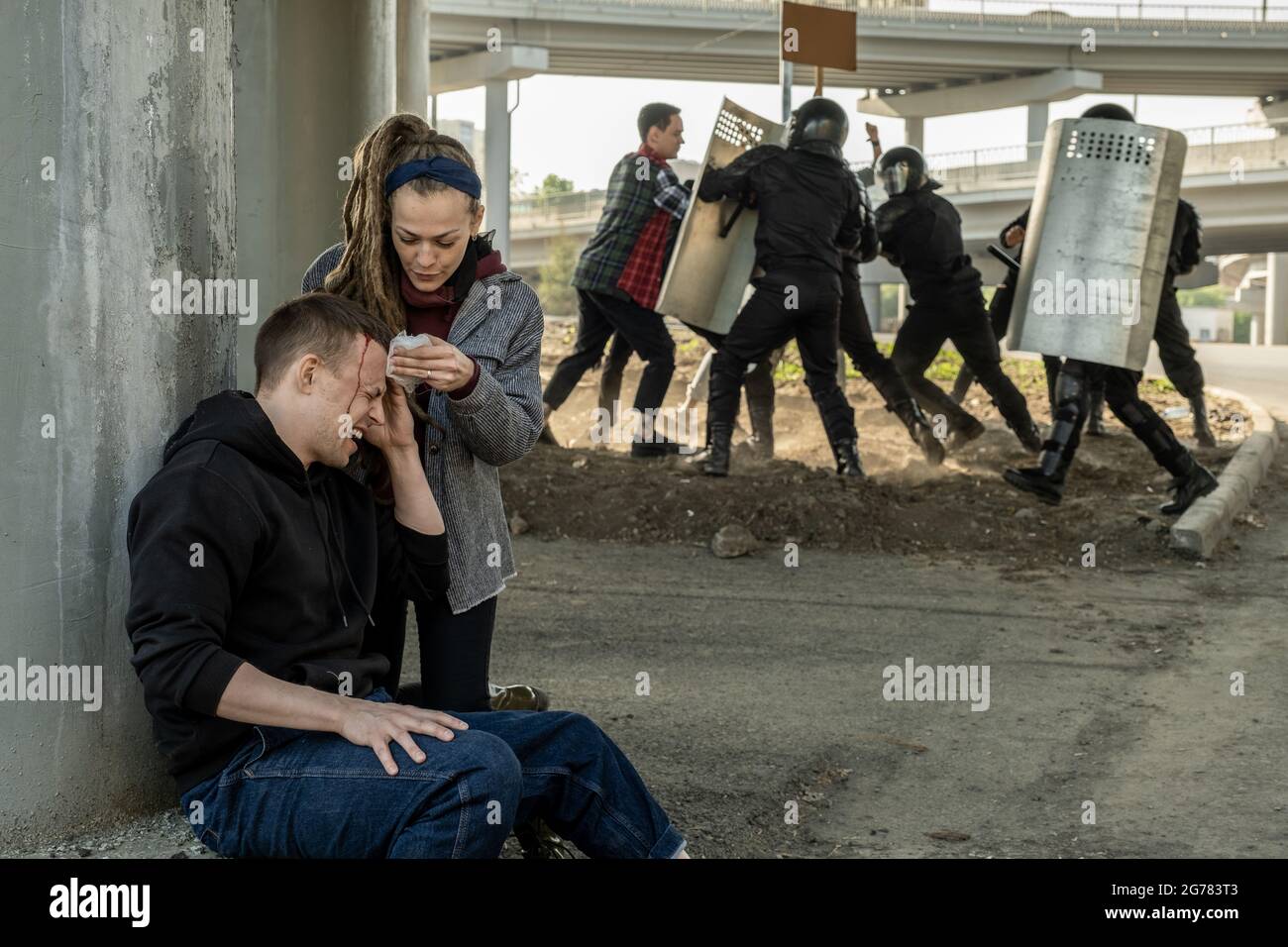 Serious young woman giving first aid to rebel suffered from fight with ...