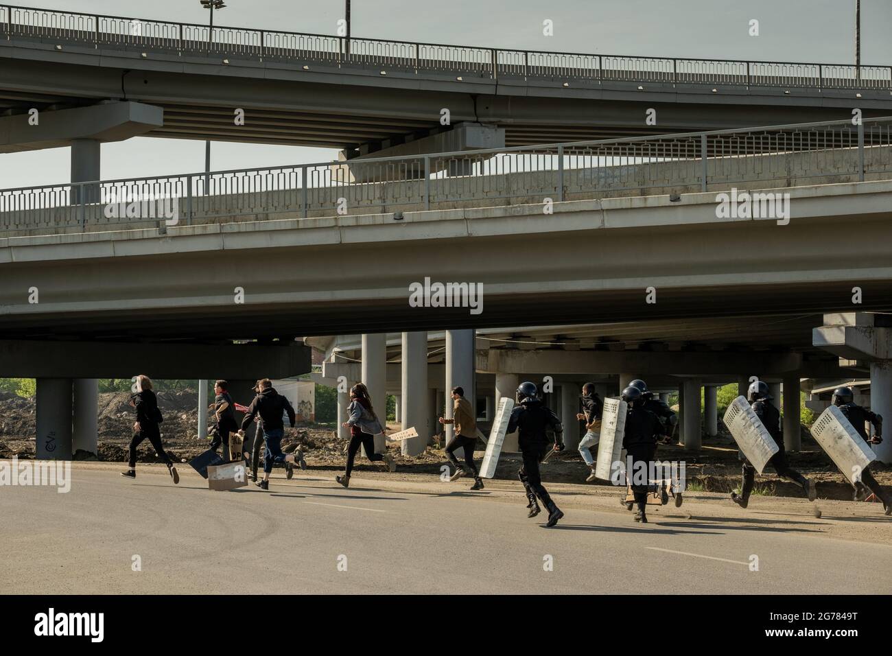 Group of young protesters with signs running from riot police after ...