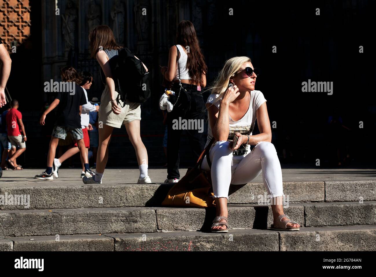 Blonde tourist sat enjoying the warm evening sunlight on cathedral ...