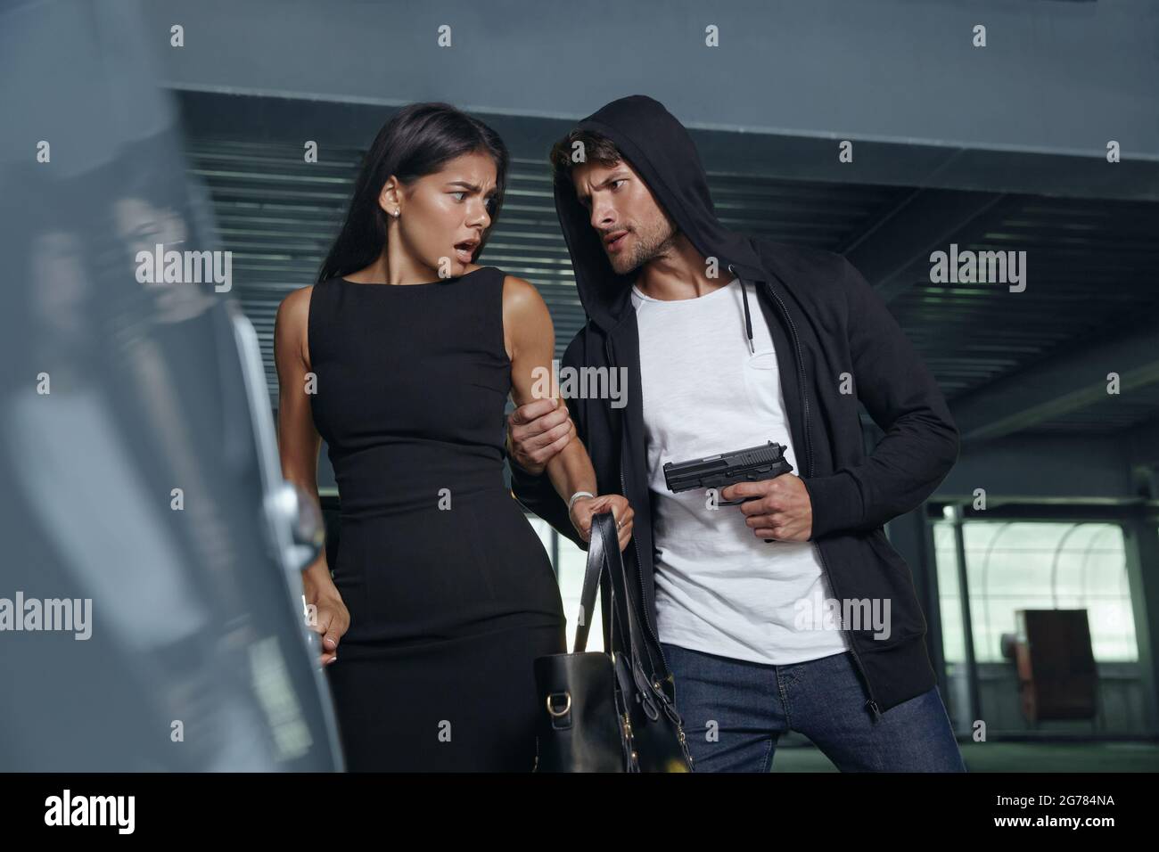 Angry robber grabbing hand of frightened girl and threatening with ...