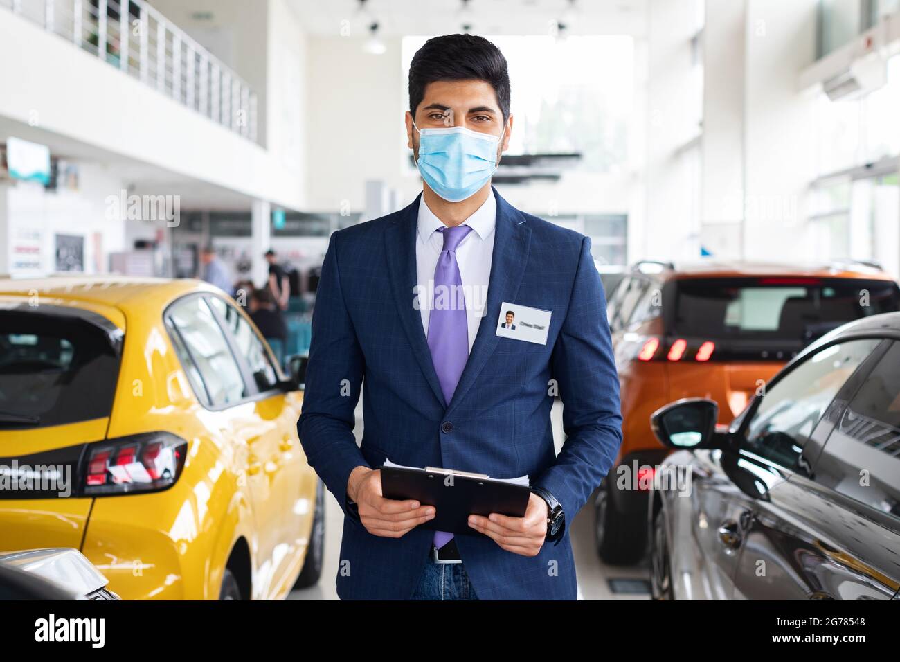 Salesman middle-eastern man in face mask posing in auto showroom Stock ...