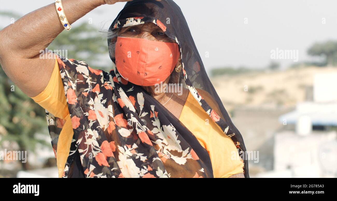 Old Indian woman wearing a traditional sari and face mask- new normal ...