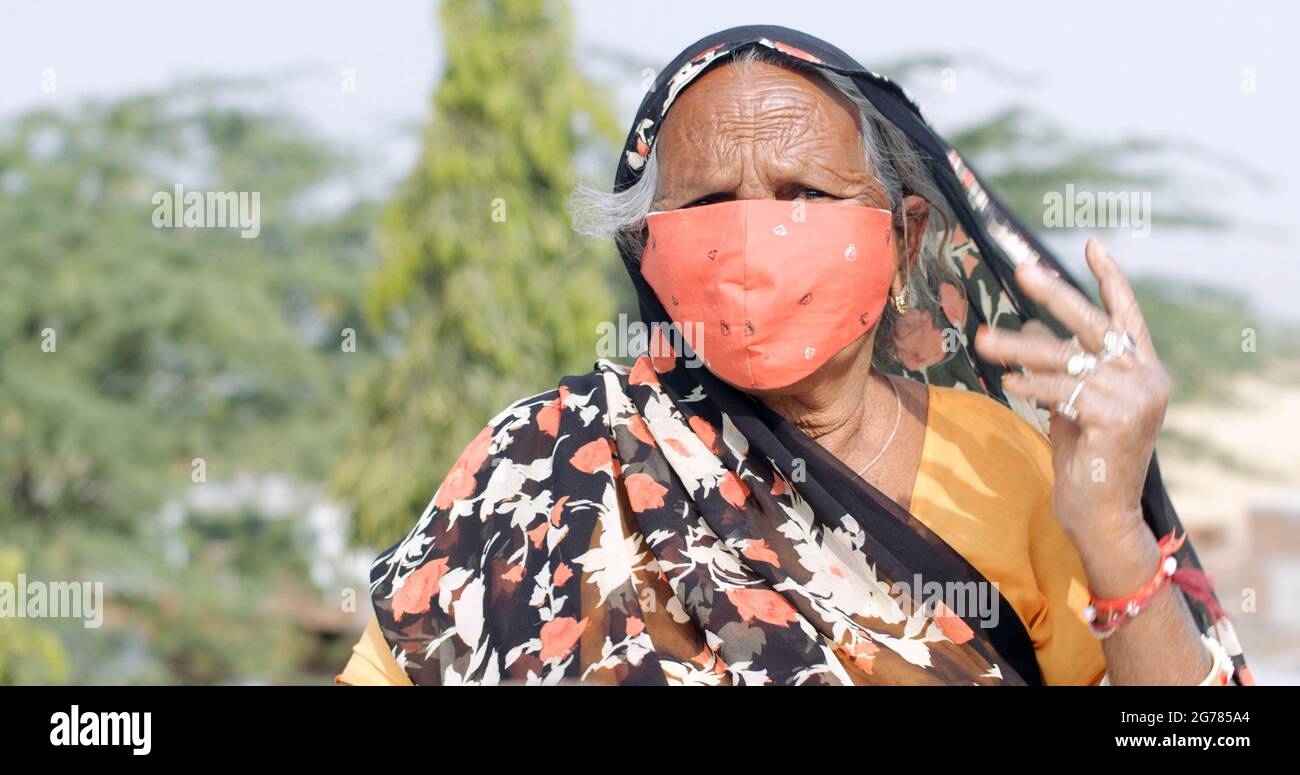 Old Indian woman wearing a traditional sari and face mask- new normal ...