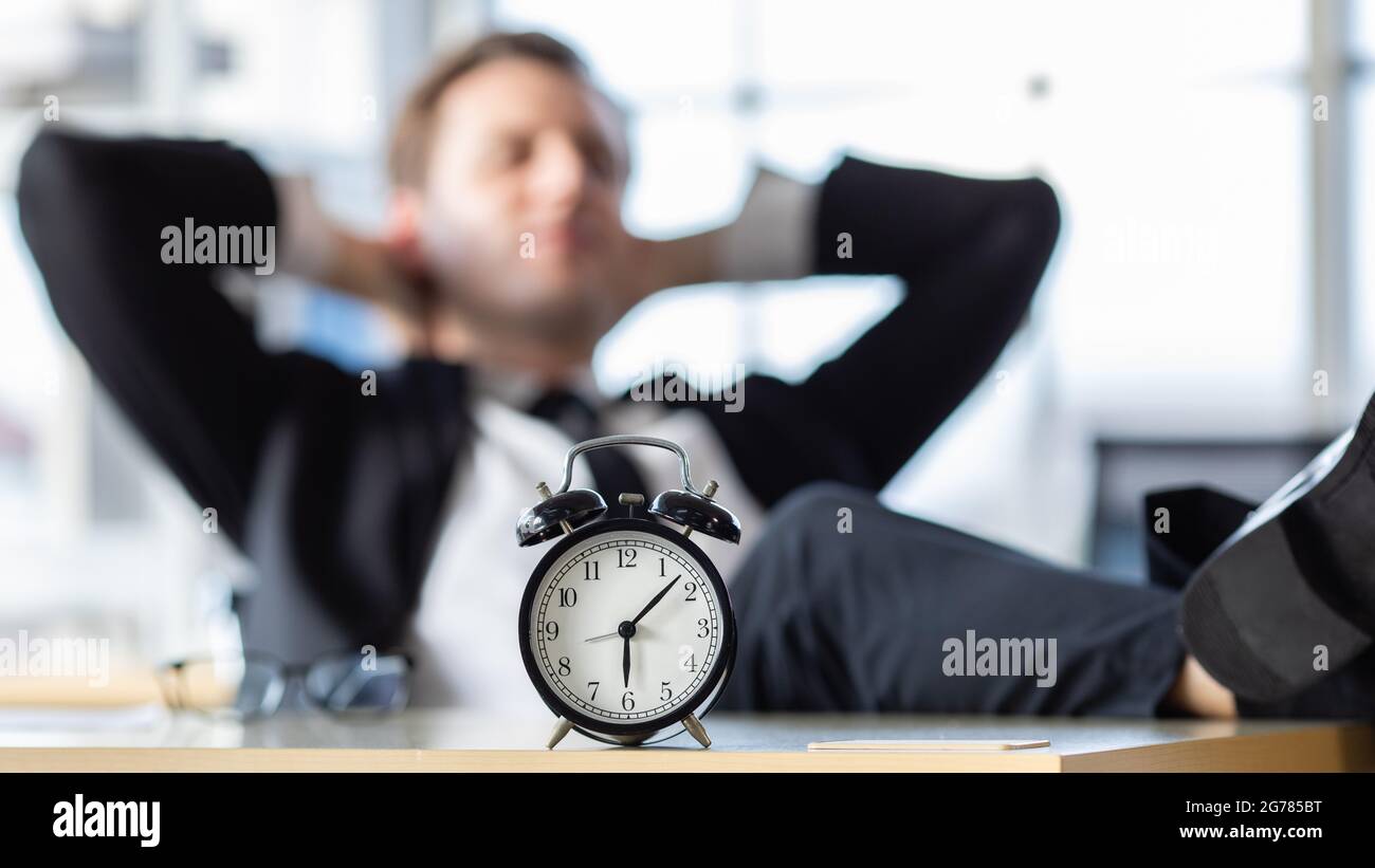 The clock shows time after office hours work on a desk with a ...