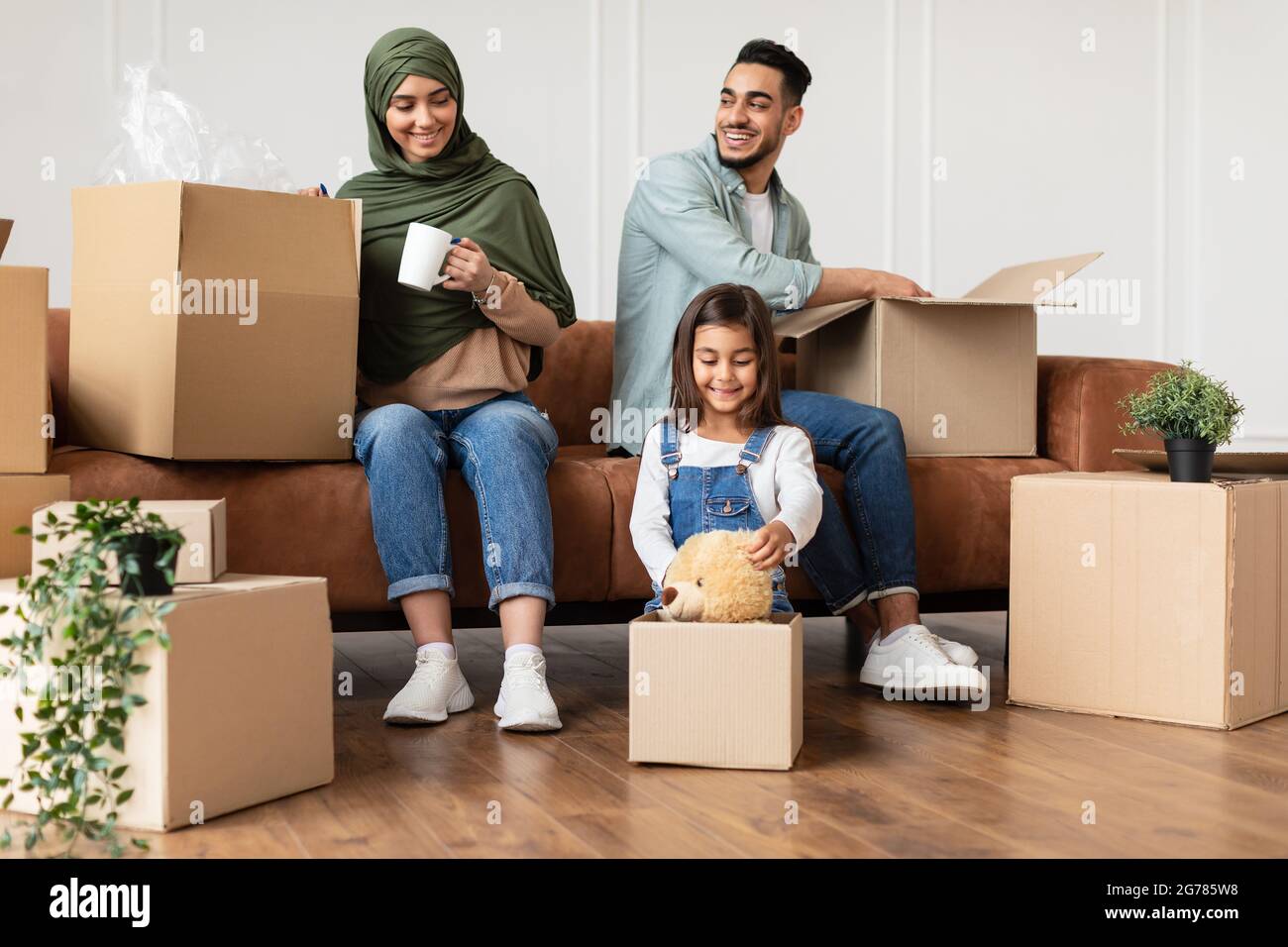 Happy man, woman and girl packing or unpacking carton boxes Stock Photo ...