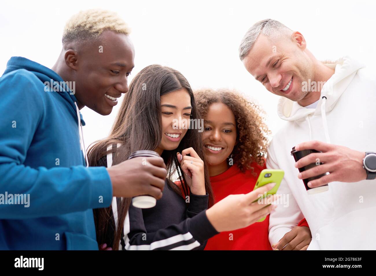 Multi-ethnic group teenage friends looking smartphone screen. African ...