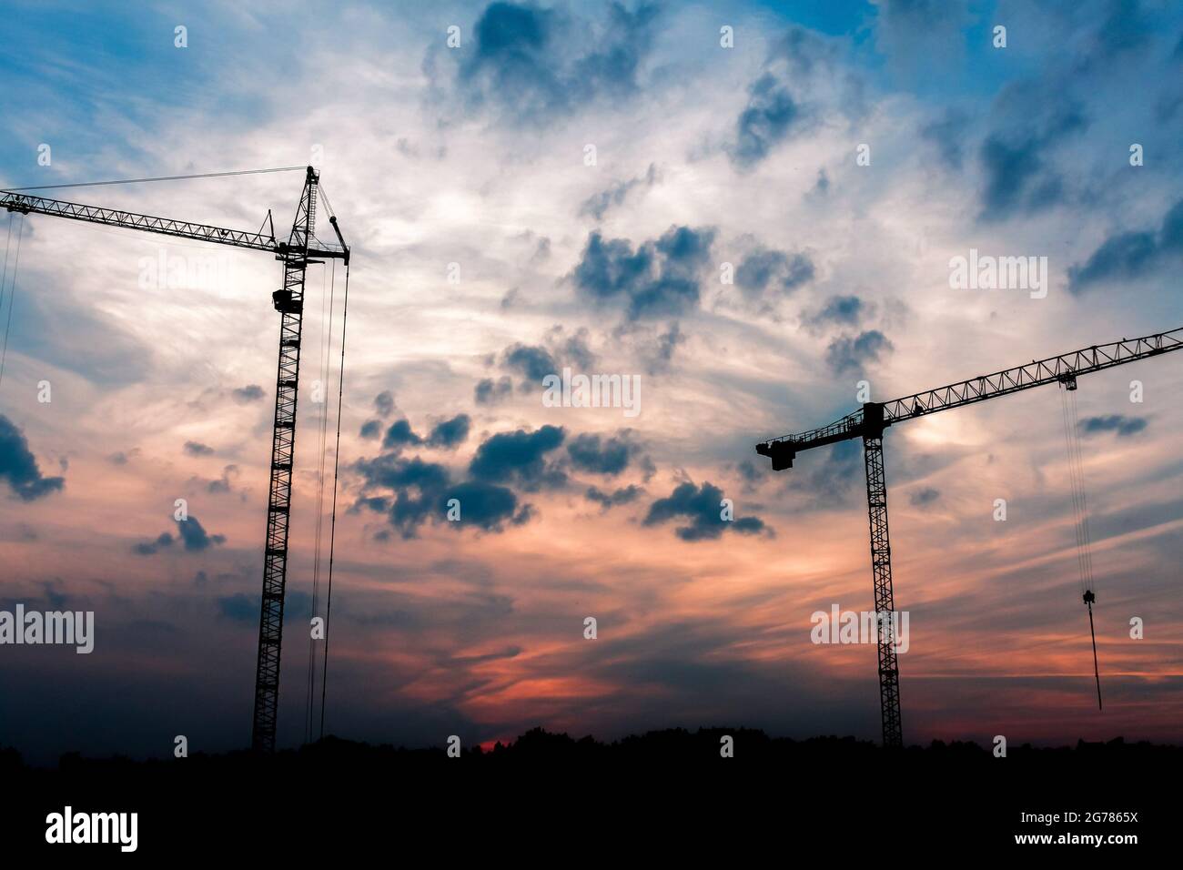 Two cranes on sunset background with clouds Stock Photo - Alamy