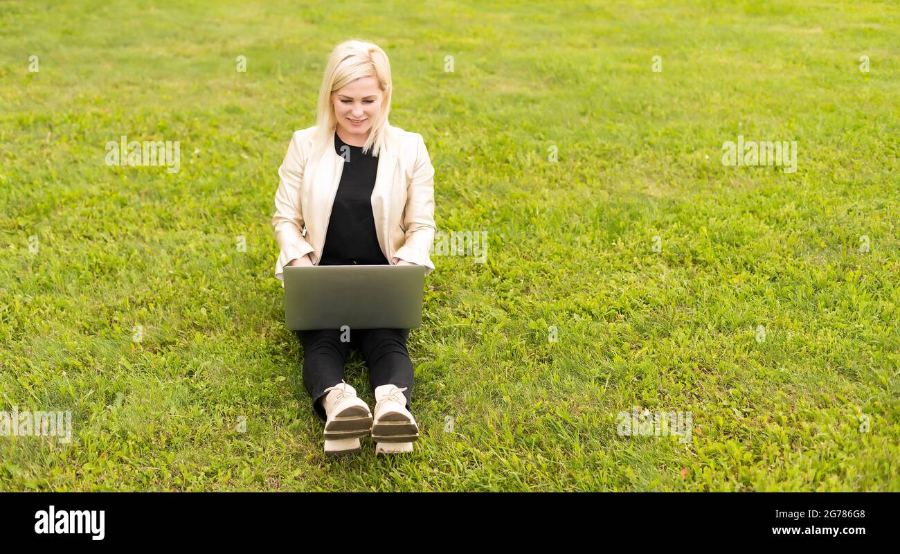 Female copywriter working on laptop in the park, view over the shoulder ...