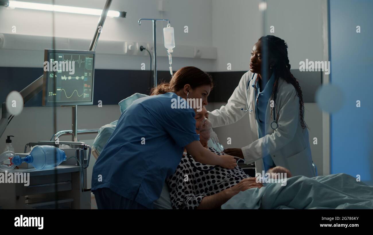 Elder patient breathing heavy in hospital ward bed with IV drip bag ...