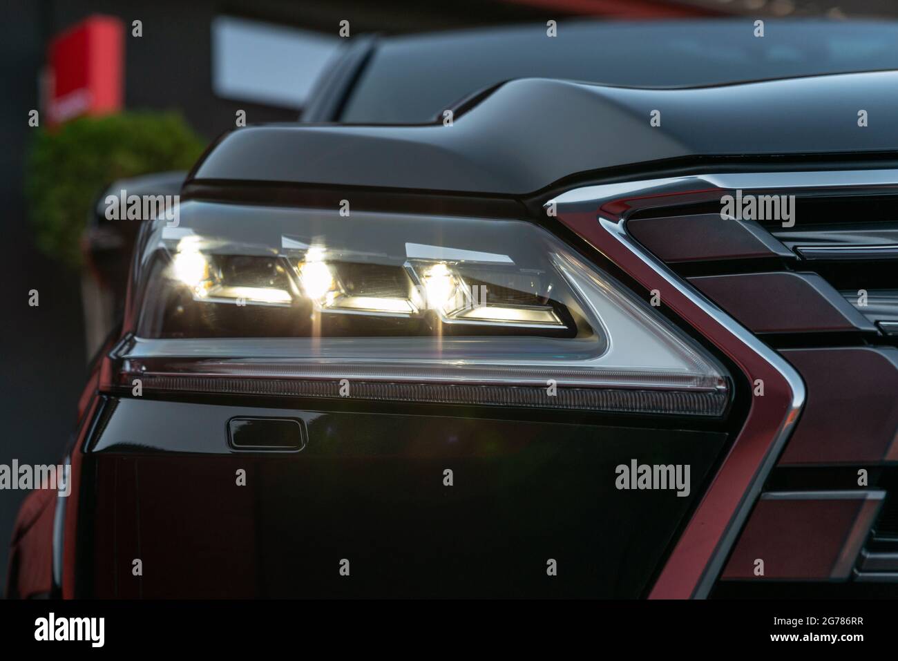 Front illuminated headlights of a black luxury modern car. Close up ...