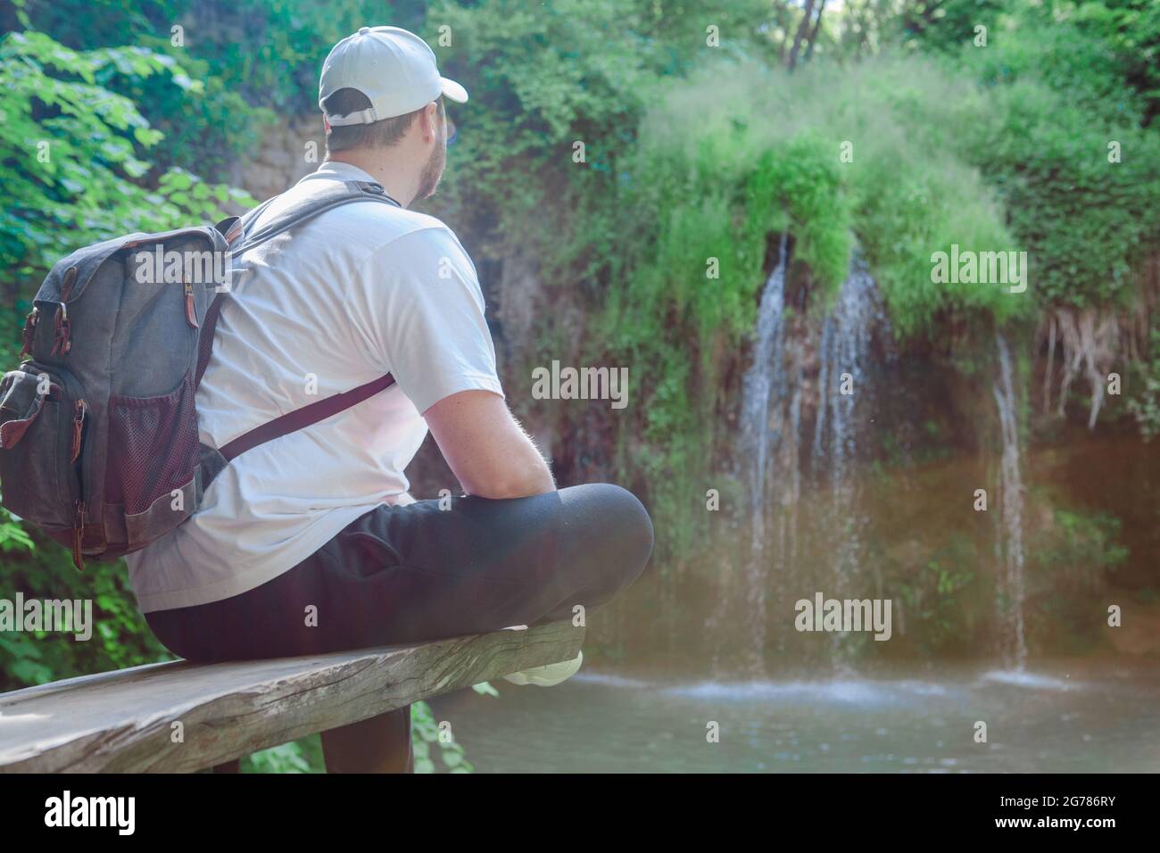 man hiker backpacker looking at waterfall with blue lake copy space ...