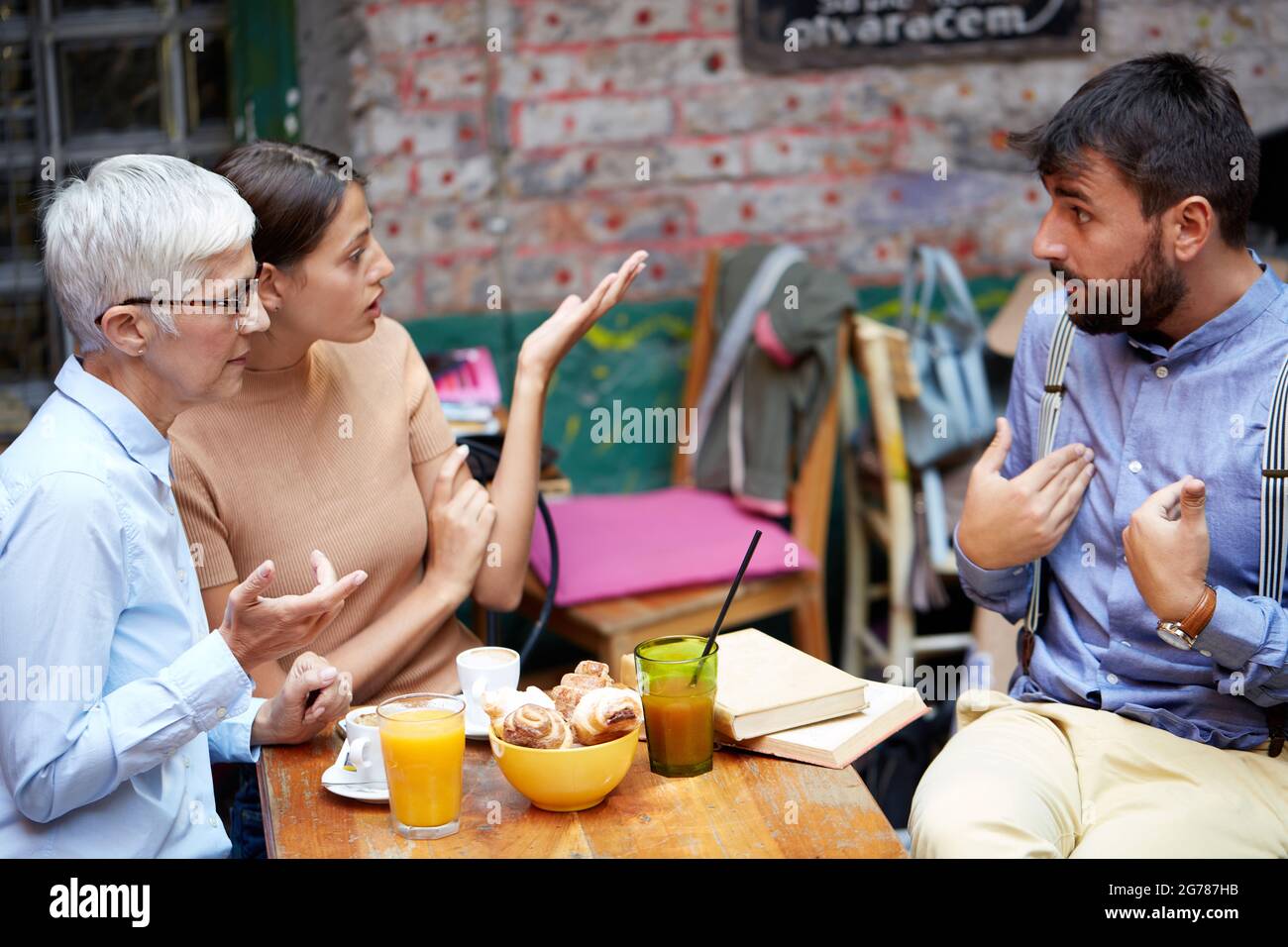 A young man arguing with his girlfriend and her Grandma while sitting ...