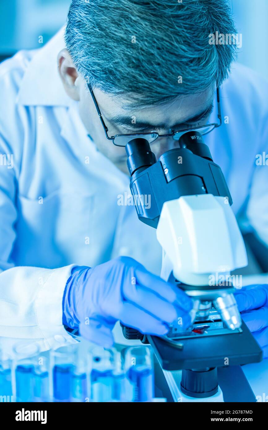 Doctor or researcher wearing eyeglasses and blue medical glove ...